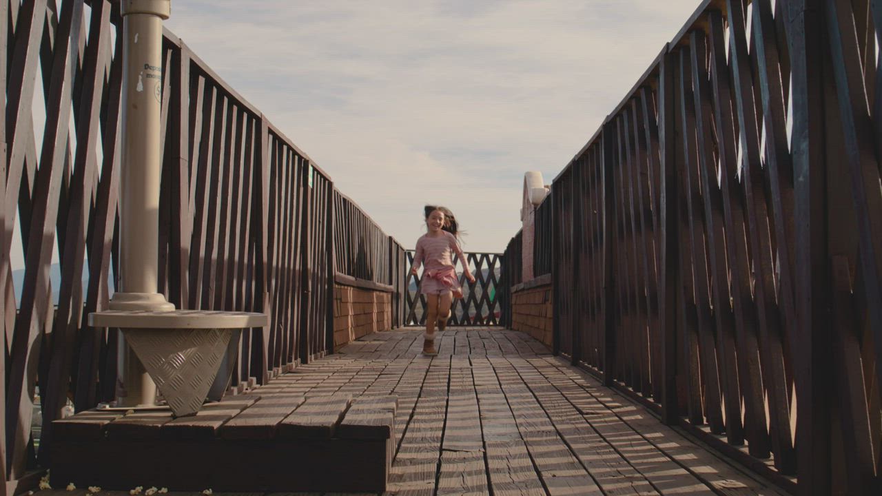 Girl running happily across a wooden bridge - Free Stock Video
