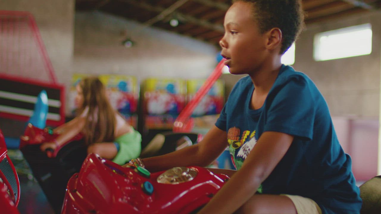 Kids enjoy racing on fast bikes at a videogame parlor - Free Stock Video