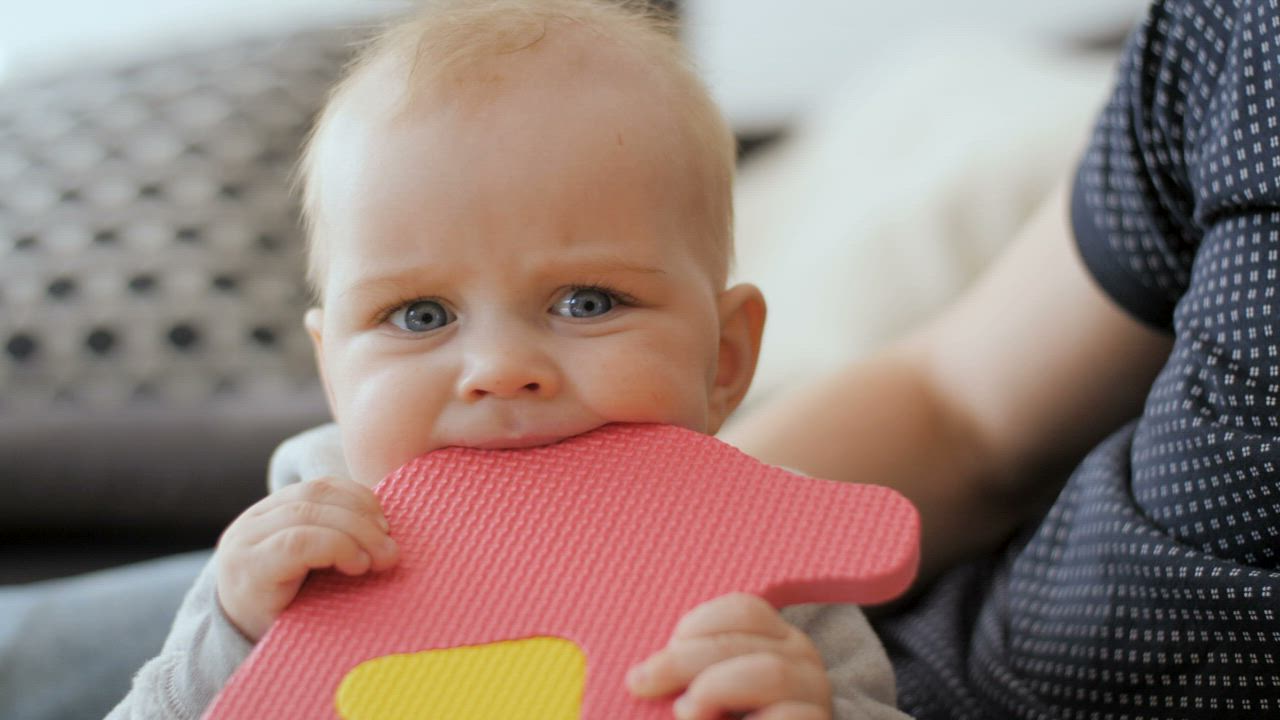 Teething baby chewing on a colourful toy - Free Stock Video