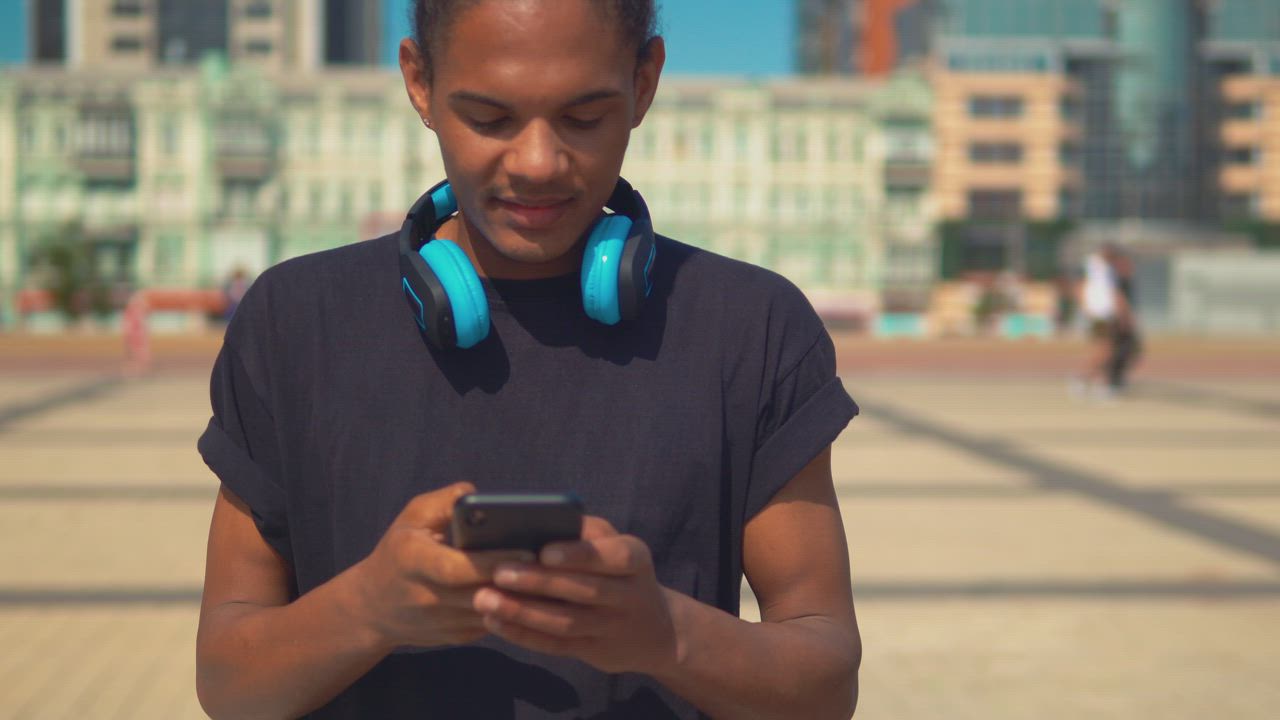 Young man on the street typing on his cell phone - Free Stock Video