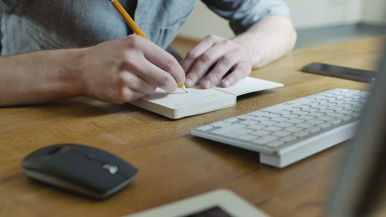 Man drawing ideas in a notebook on his work desk - Free Stock Video