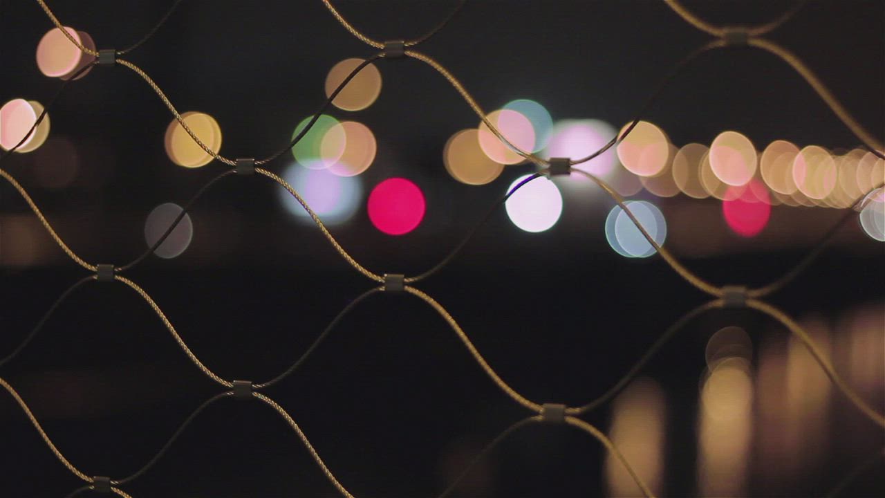 Close up of wire fence with city lights background - Free Stock Video