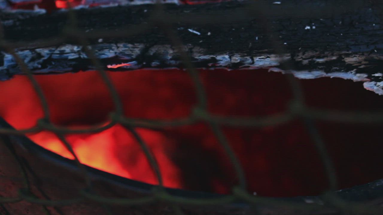 Close up fire in barrel behind wire fence - Free Stock Video