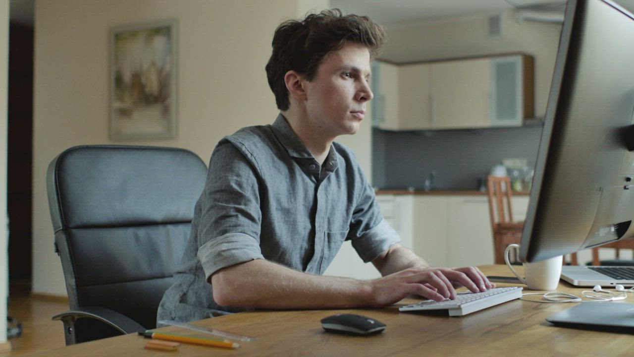 Intensely focused young man working on a computer - Free Stock Video