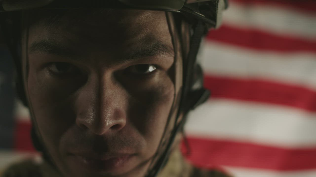 Young soldier looking up at the camera with the USA flag behind him ...