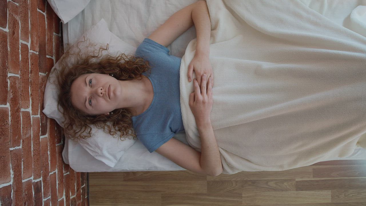Young woman staring up at the ceiling in her bed - Free Stock Video