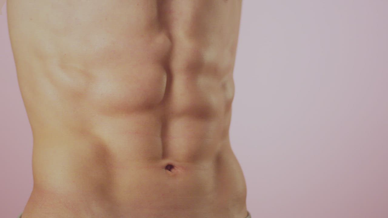 Close up of a mans abs against a pink background - Free Stock Video