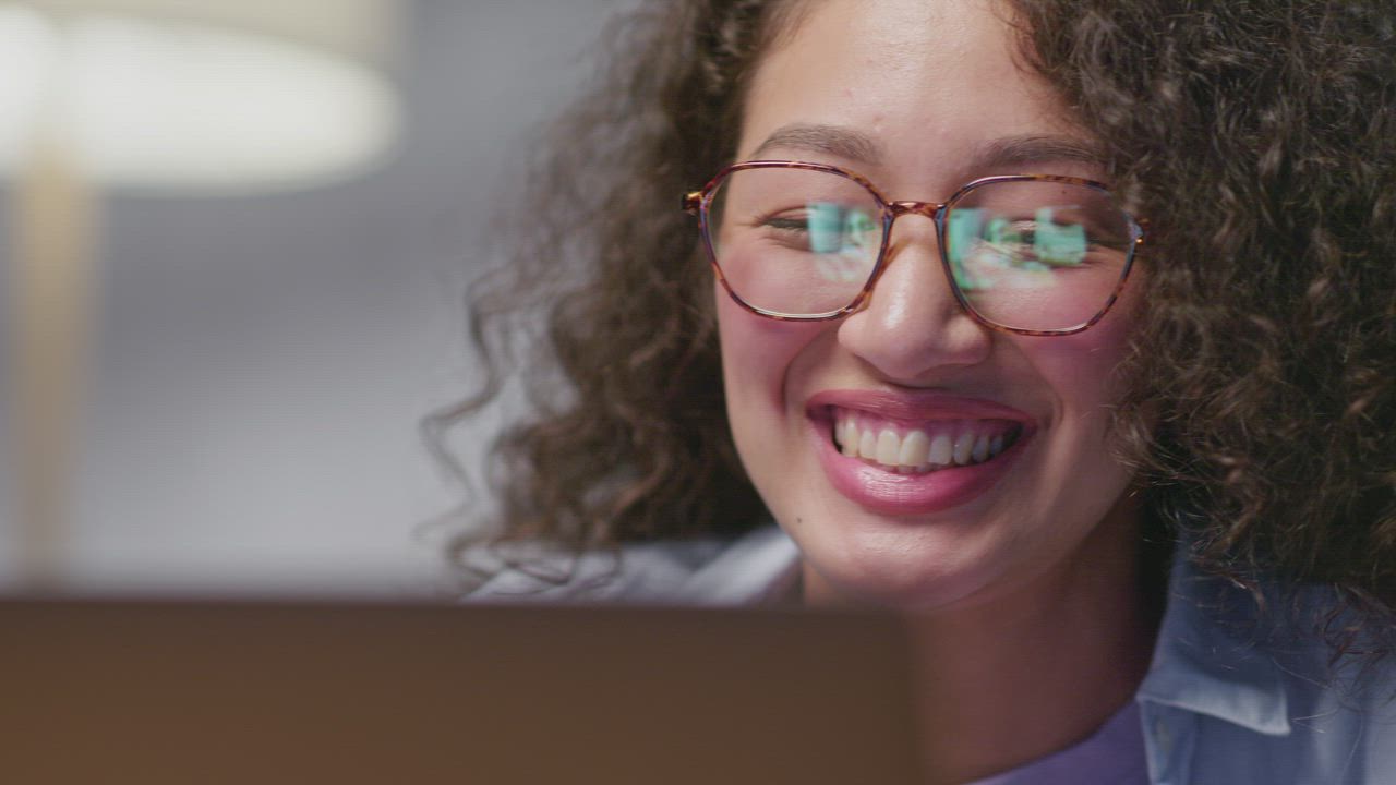 Young woman smiling and waving in greeting to people on a live webinar ...