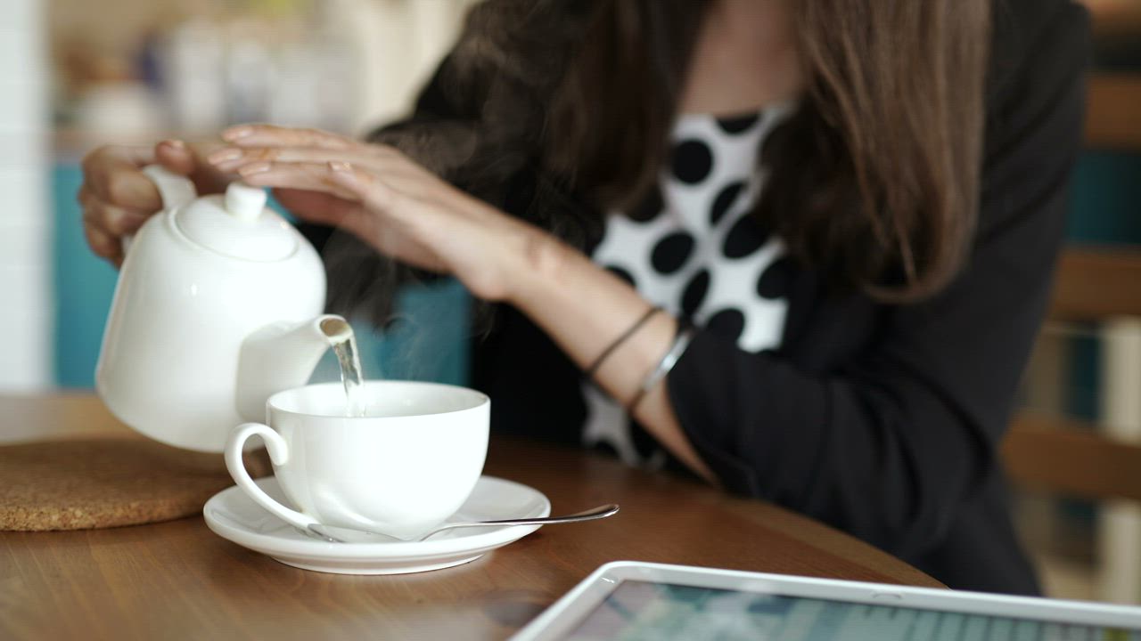 Woman pouring tea into a tea cup - Free Stock Video
