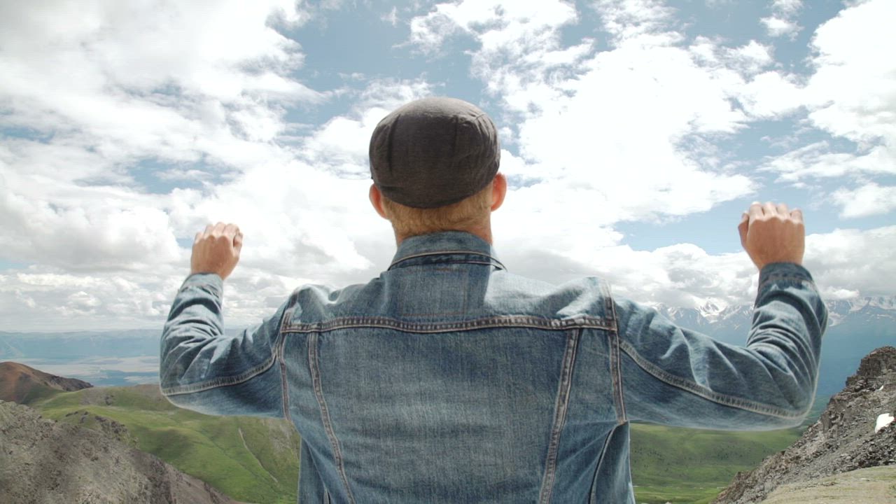 Man standing on top of a mountain on a bright day - Free Stock Video