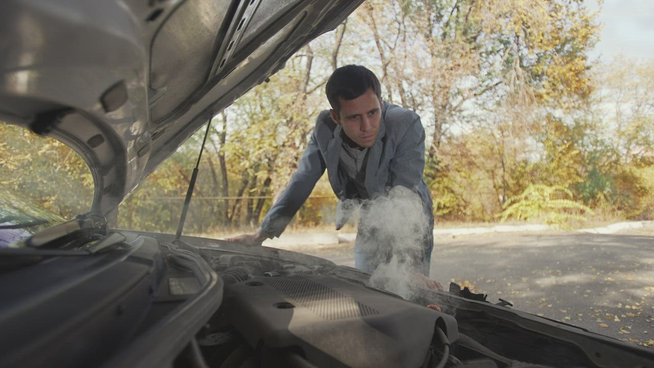 Man leaning over a brokendown car engine - Free Stock Video