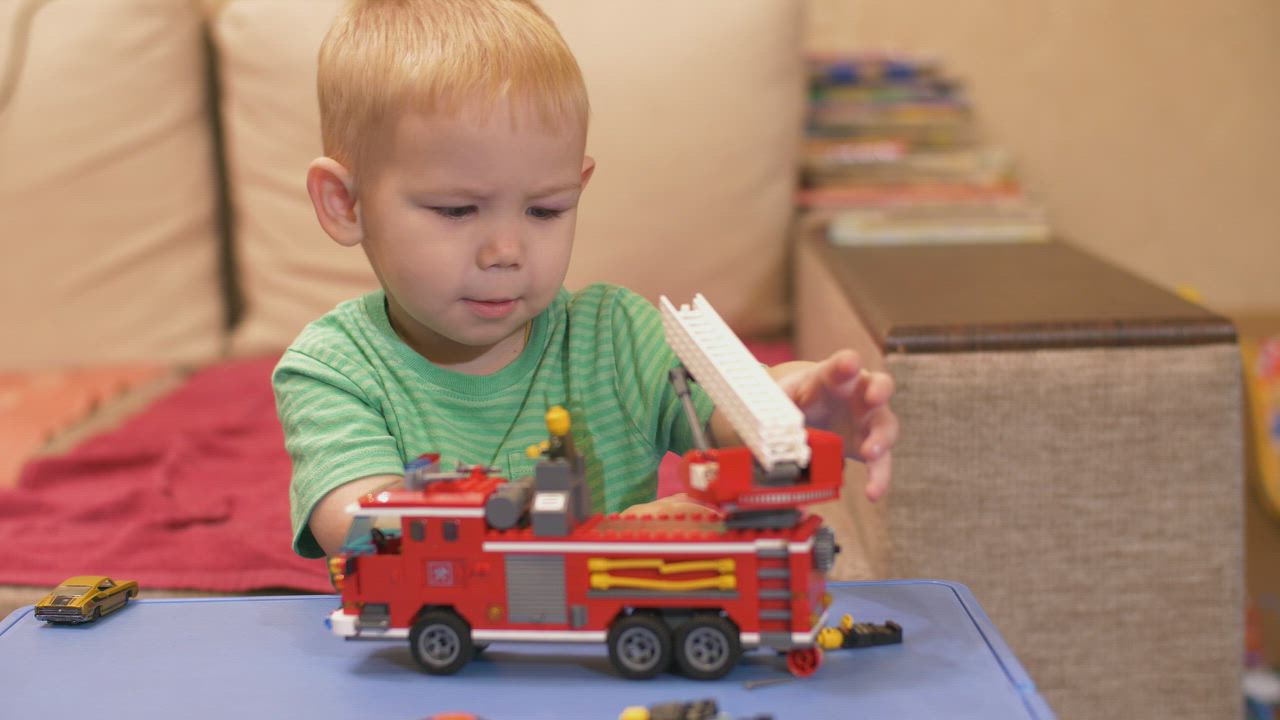 Young boy plating with a toy fire engine - Free Stock Video