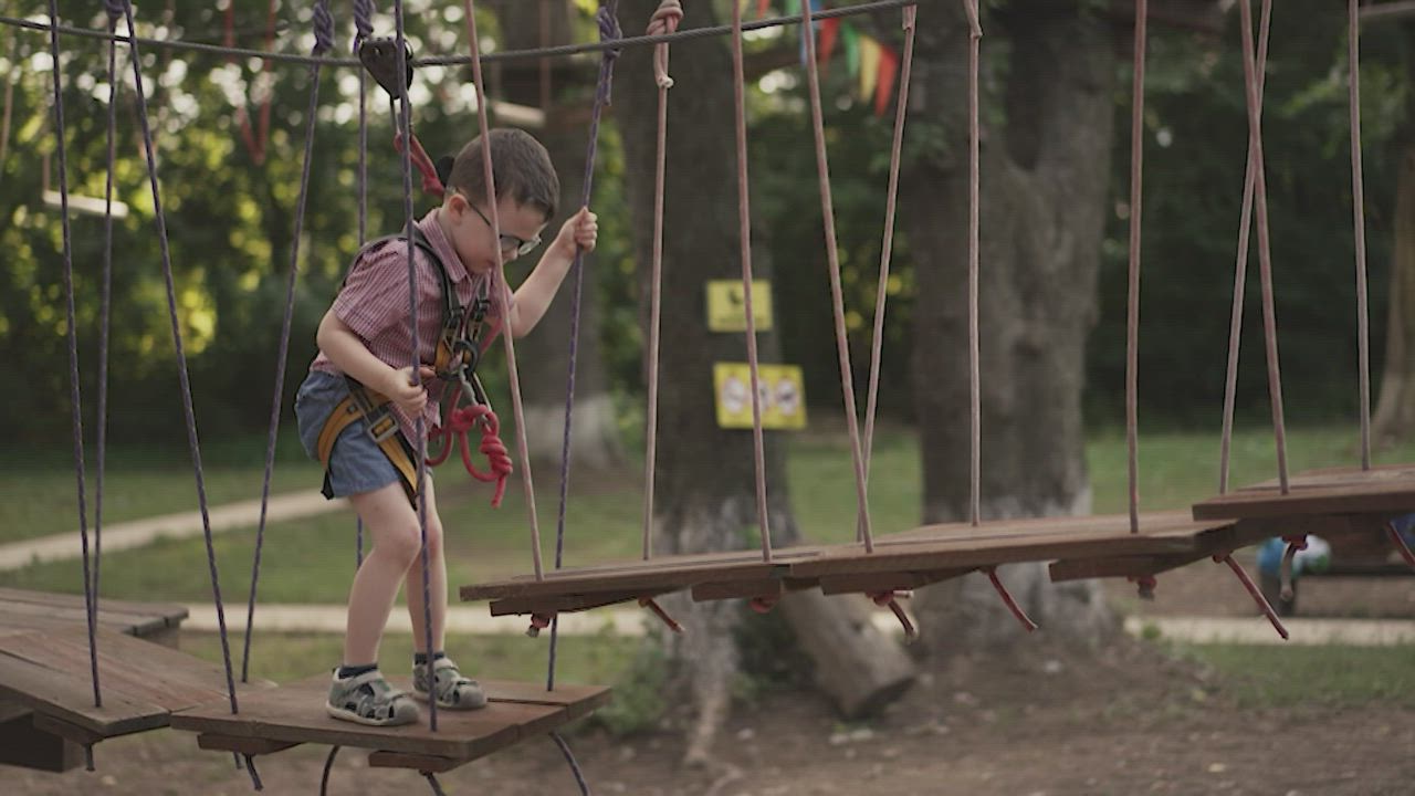 Young boy navigating a rope bridge in a playground - Free Stock Video
