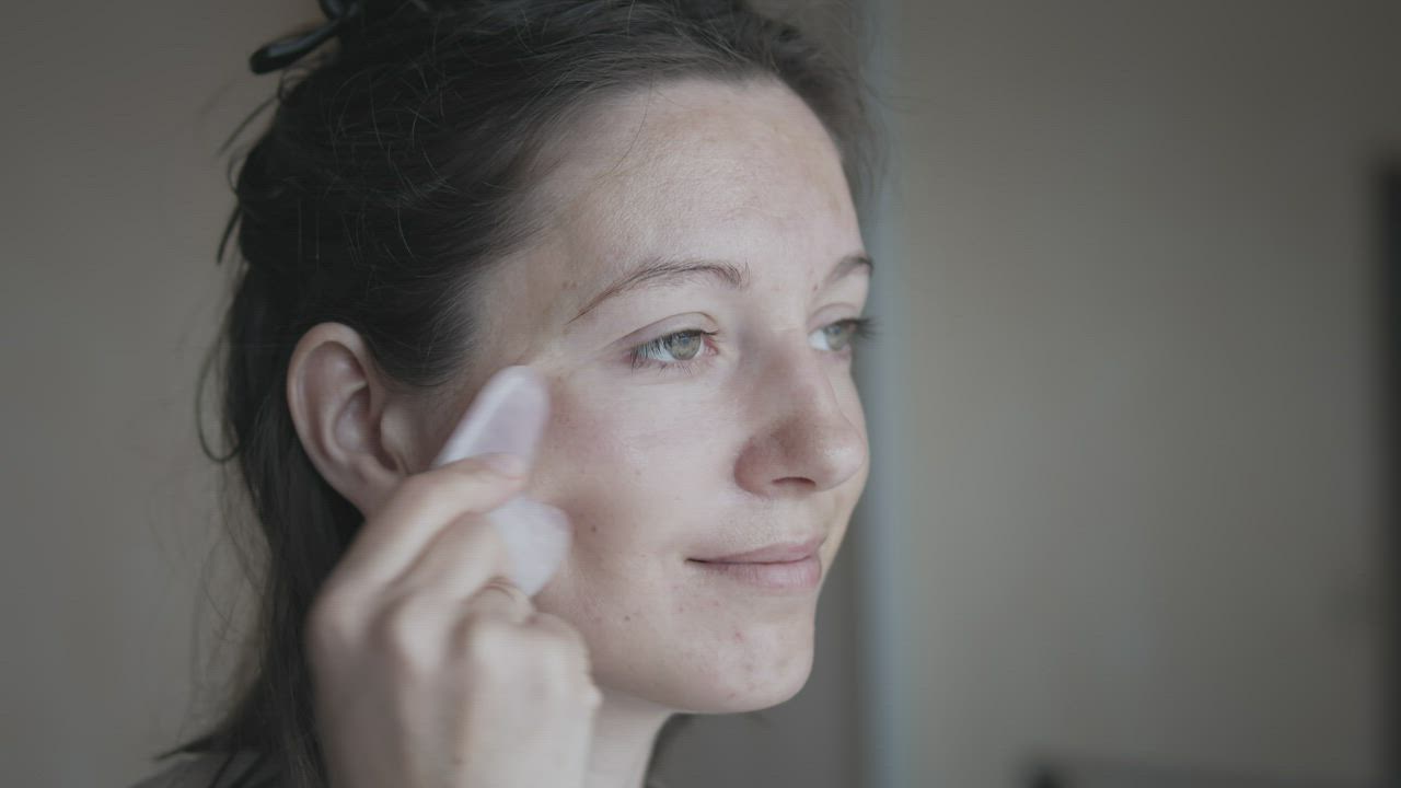Woman doing Gua Sha on her face - Free Stock Video