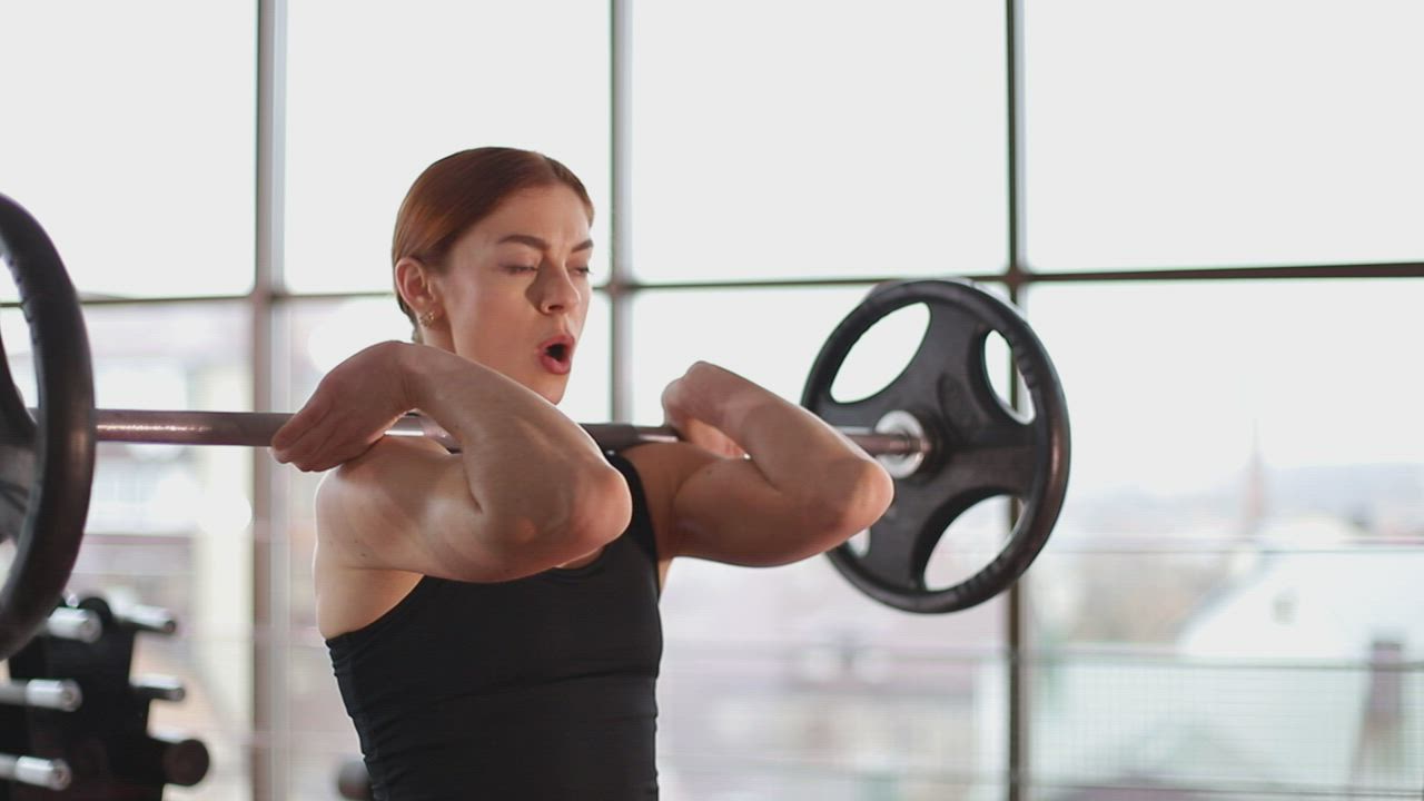 A woman lifts a barbell in the gym, a fitness woman does strength exer ...