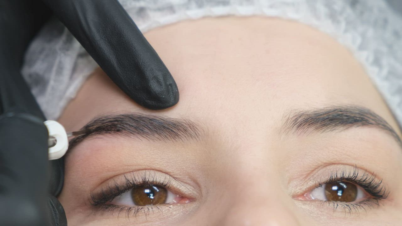 Microblading technician applying pigmentation on eyebrow - Free Stock Video