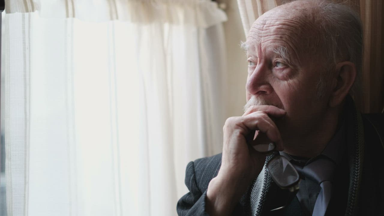 Elderly man looks out of his window with a hopeful look - Free Stock Video