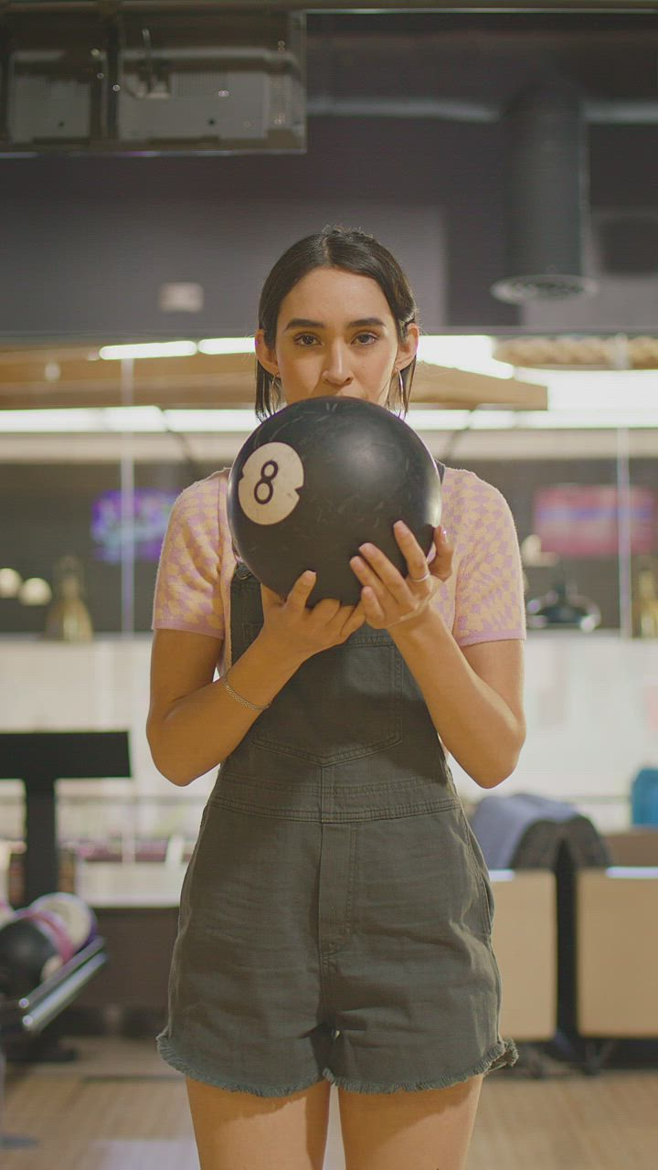 Vertical shot of a young woman making a bowling shot with a black bowling ball - Free Stock Video