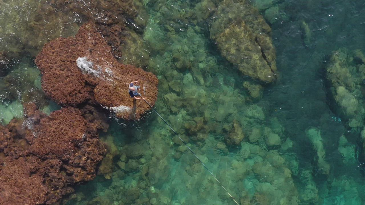 Aerial view of a fisherman casting a line on the rocky shore - Free ...