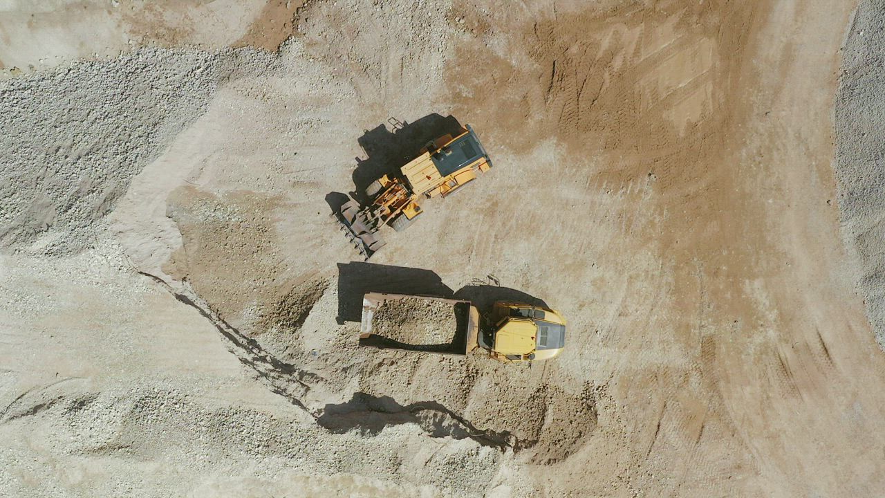 Backhoe excavating dirt at a mining site - Free Stock Video