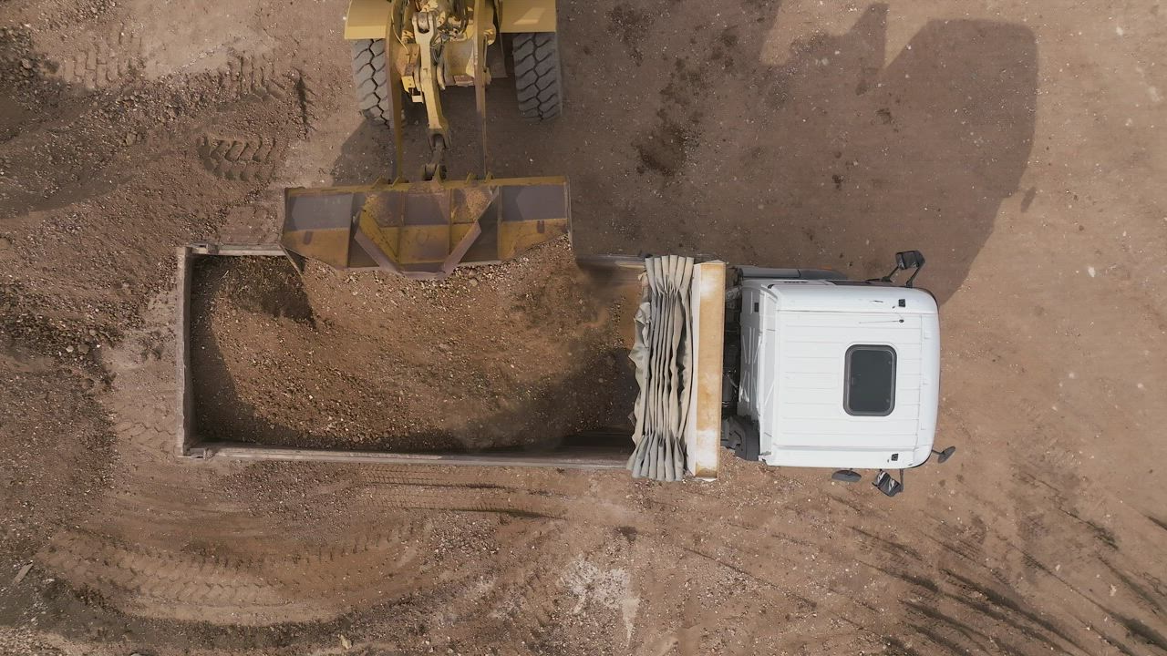 Aerial view of a bucket loader tipping dirt into a loader - Free Stock ...