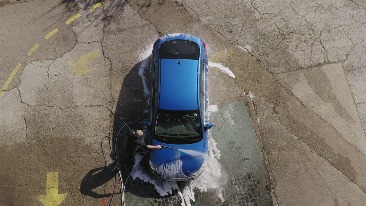 Aerial view of a man washing his blue car - Free Stock Video