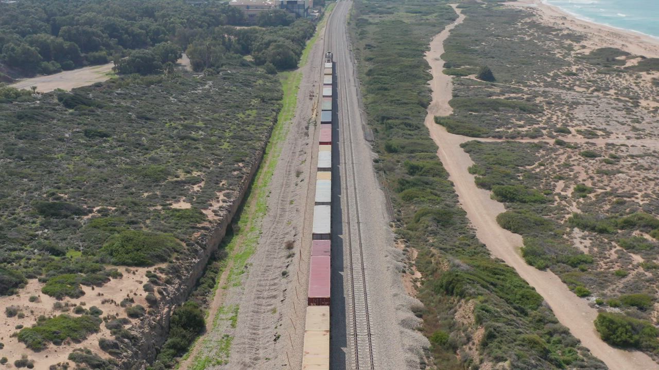 Freight train moving along the tracks next to the ocean - Free Stock Video