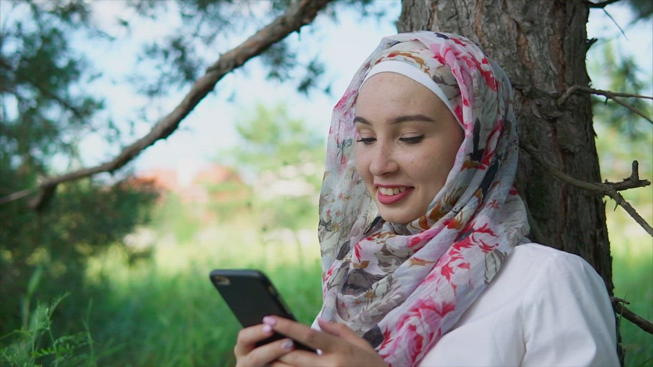 Smiling Muslim woman chatting on her cell phone with friends - Free ...
