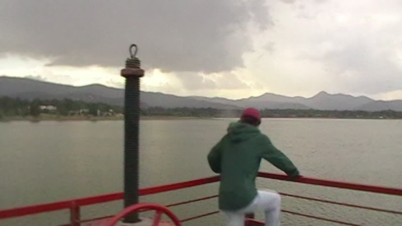 A young man climb the railing of a dam and makes poses to the camera ...