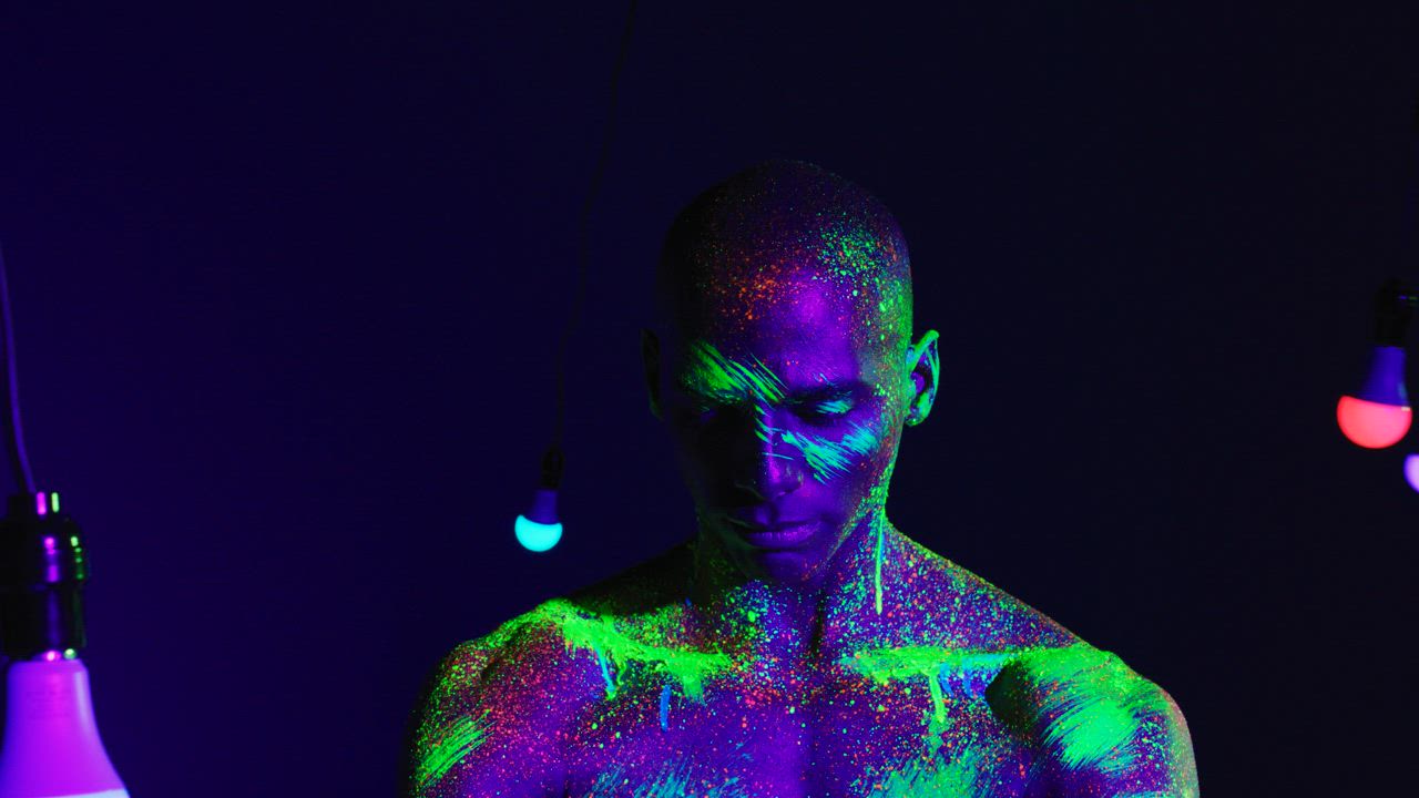 Face of a serious man with splattered fluorescent paint - Free Stock Video