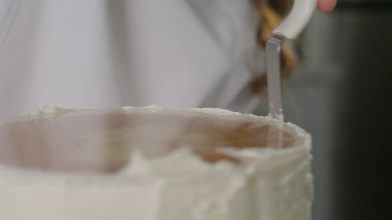 Covering a cake with icing in a close shot - Free Stock Video