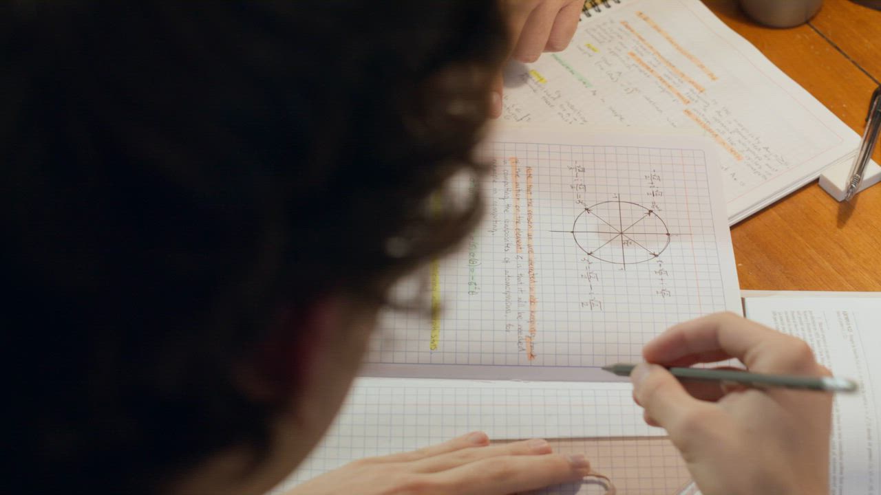 Teacher points with his finger to a mathematical chart over the student ...