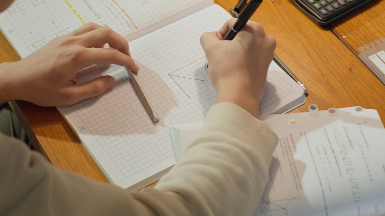 A young student is drawing a mathematical chart in the squared notebook ...