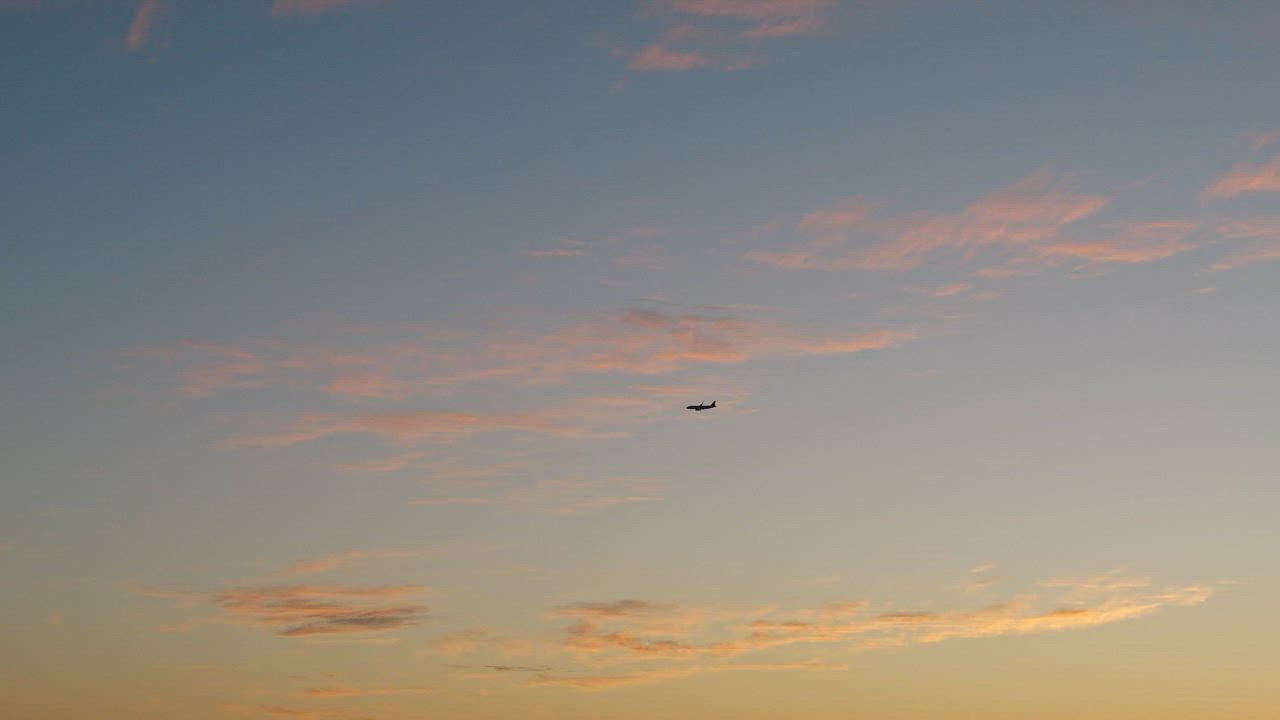 Sky view at sunset with an airplane in the distance - Free Stock Video