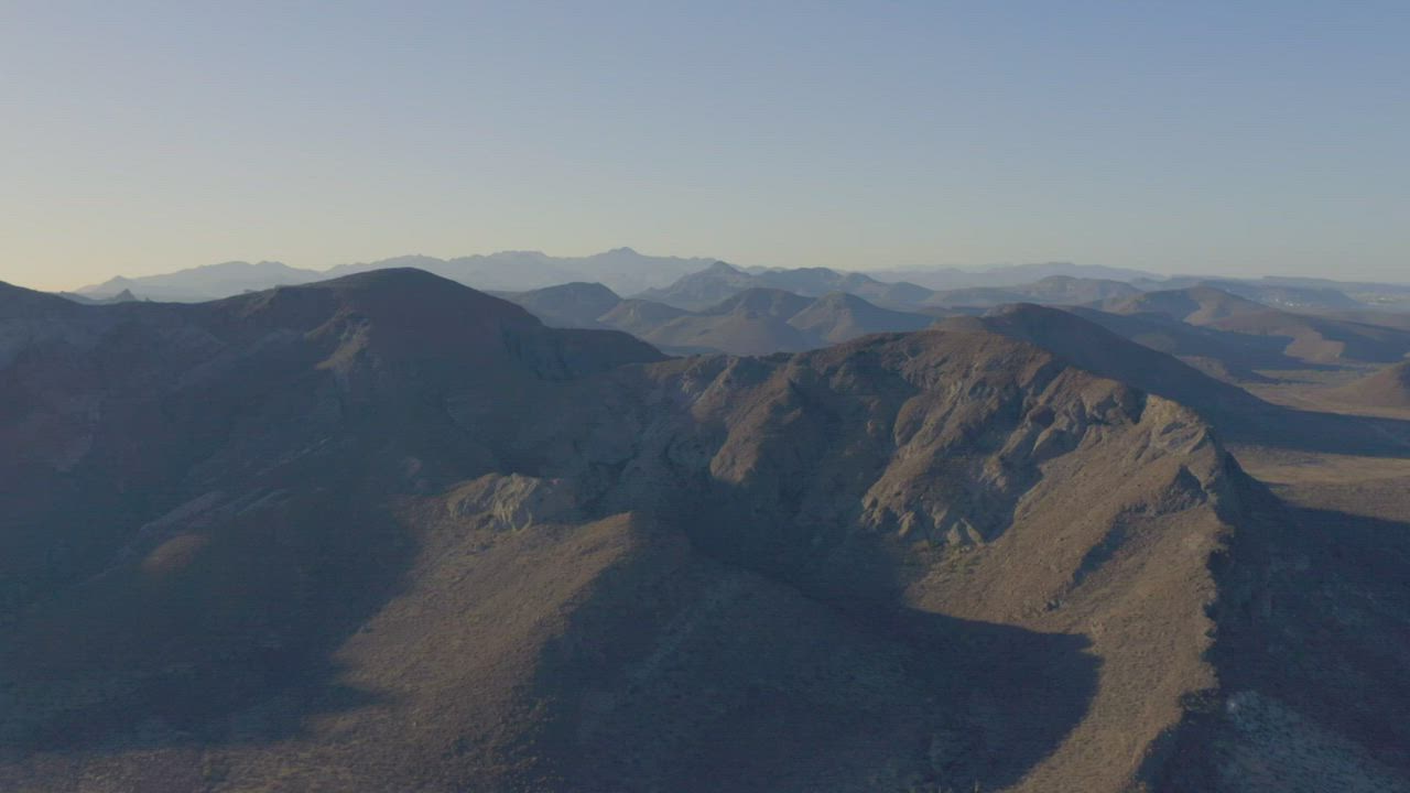 Flying over a large mountain range in an arid climate - Free Stock Video