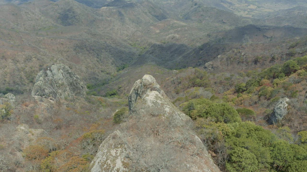 Drone aerial view of a rocky mountain with a valley in the distance ...