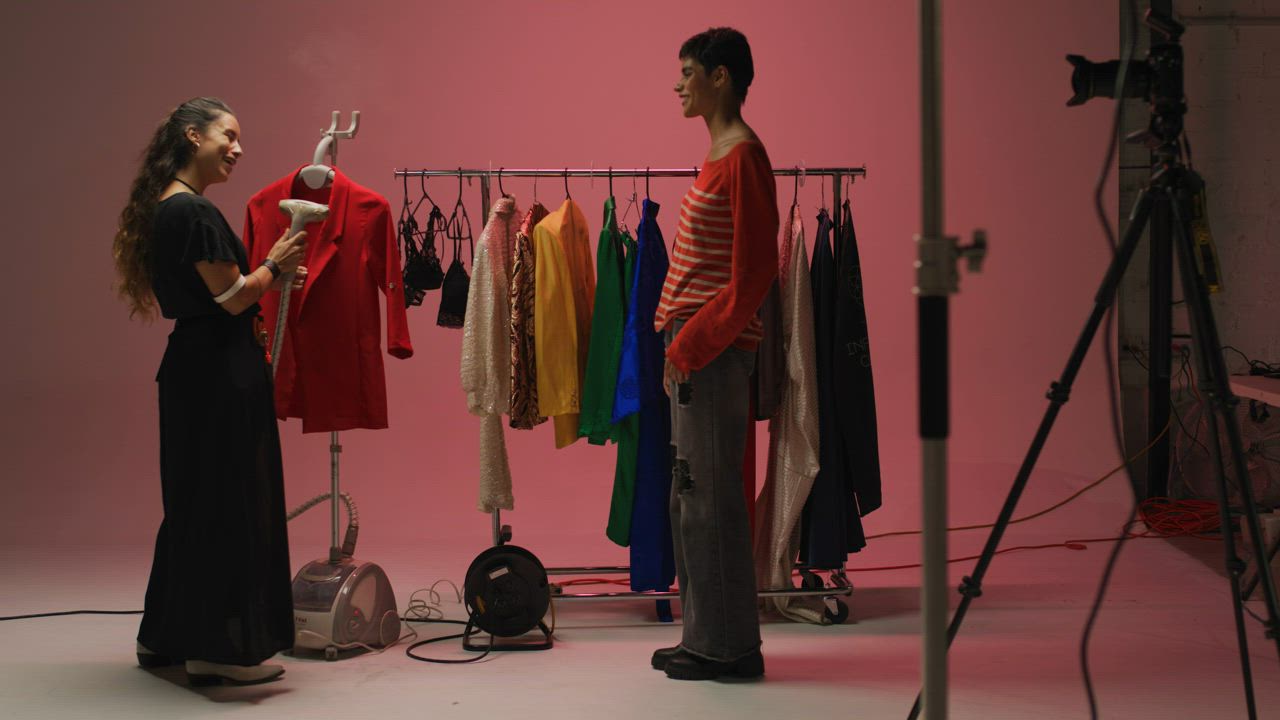 A costume designer styles a model with a red suit jacket - Free Stock Video
