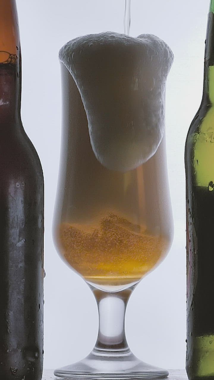Beer foam spilling into a glass on white background - Free Stock Video
