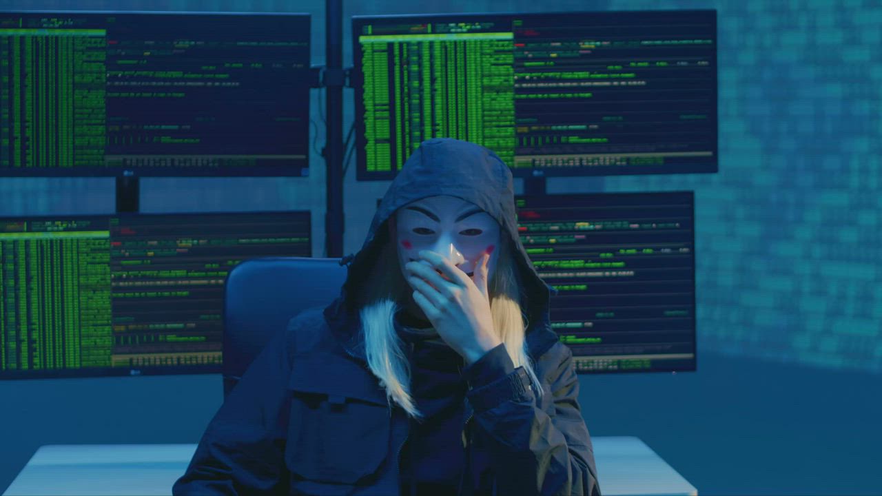 Person in an anonymous mask sits in front of computer screens - Free ...