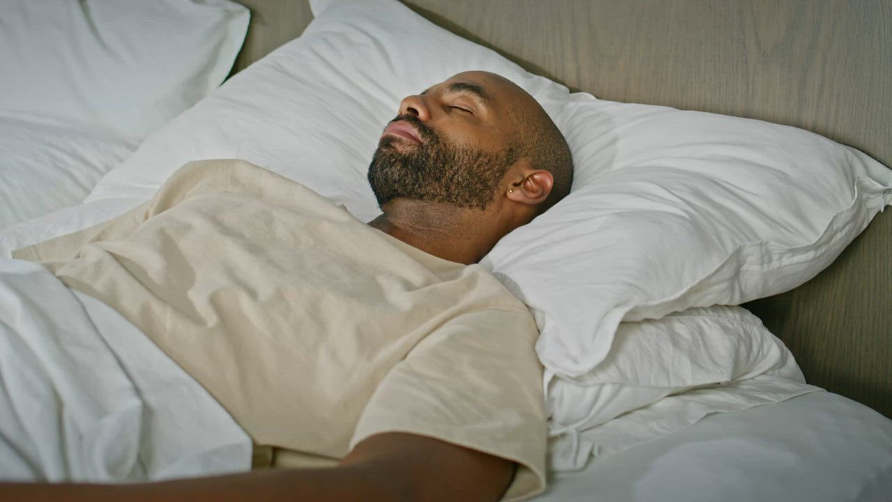 A young man slowly wakes up in bed - Free Stock Video