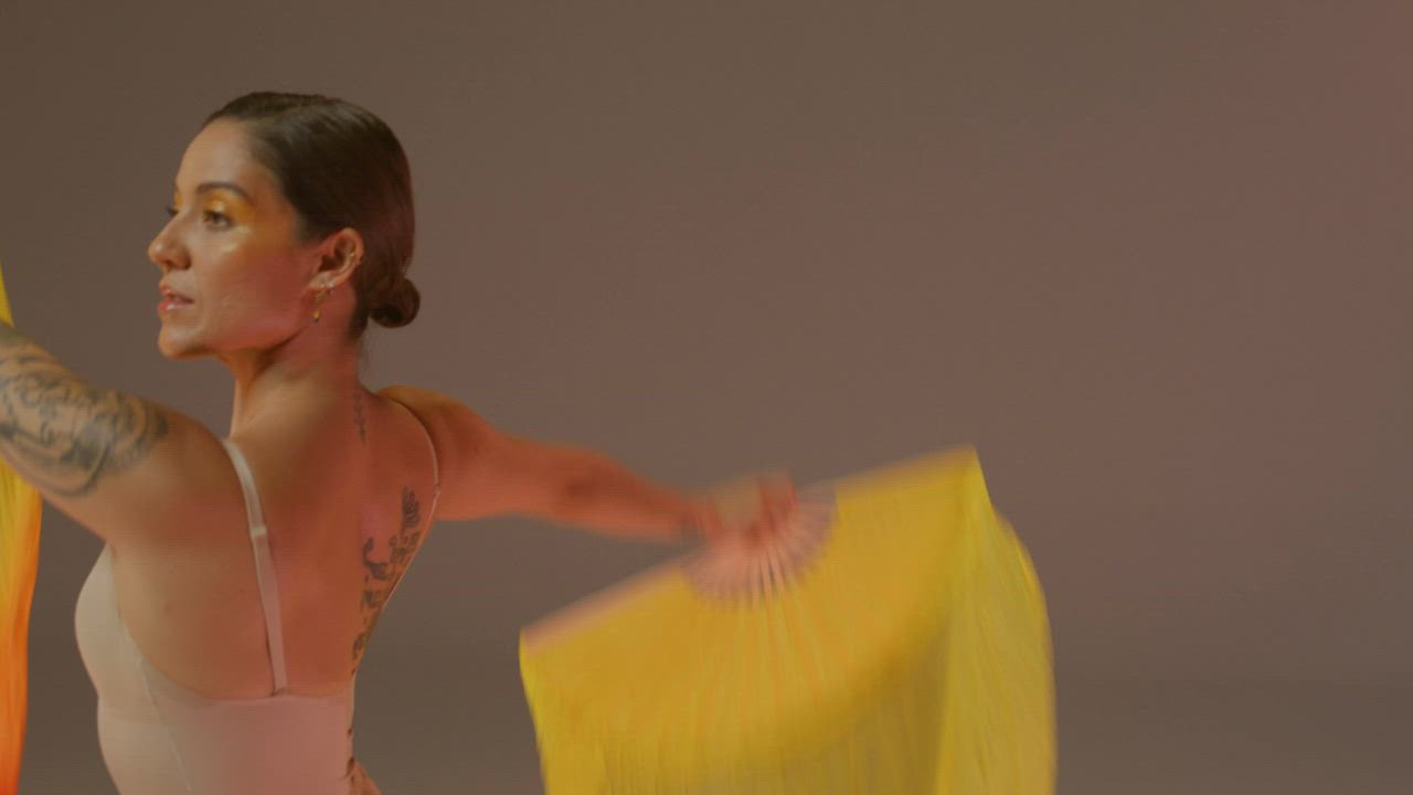 A young artist dances in fluid motion with ribbon fans that twist and ...