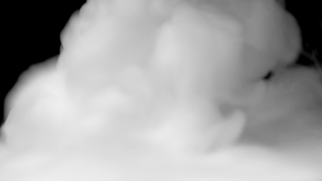 A thick mist twists and settles on a dark surface - Free Stock Video