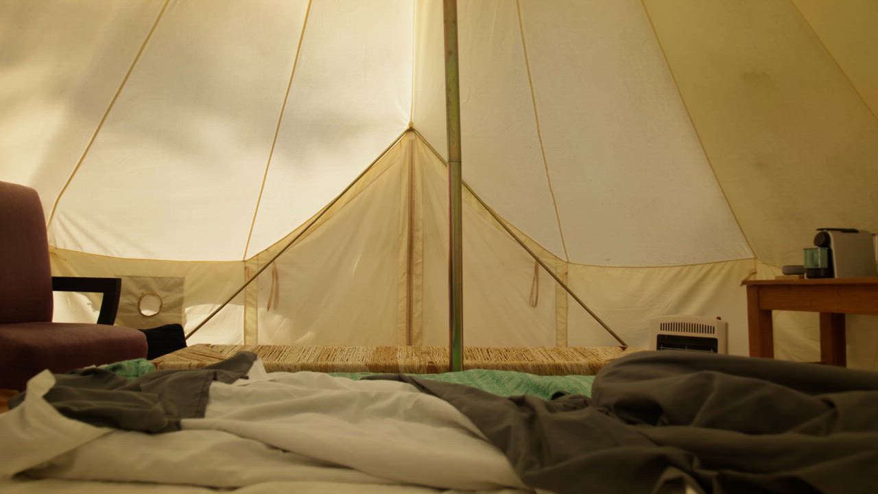 In the cozy inside of a camping tent a young man opens the main tent ...