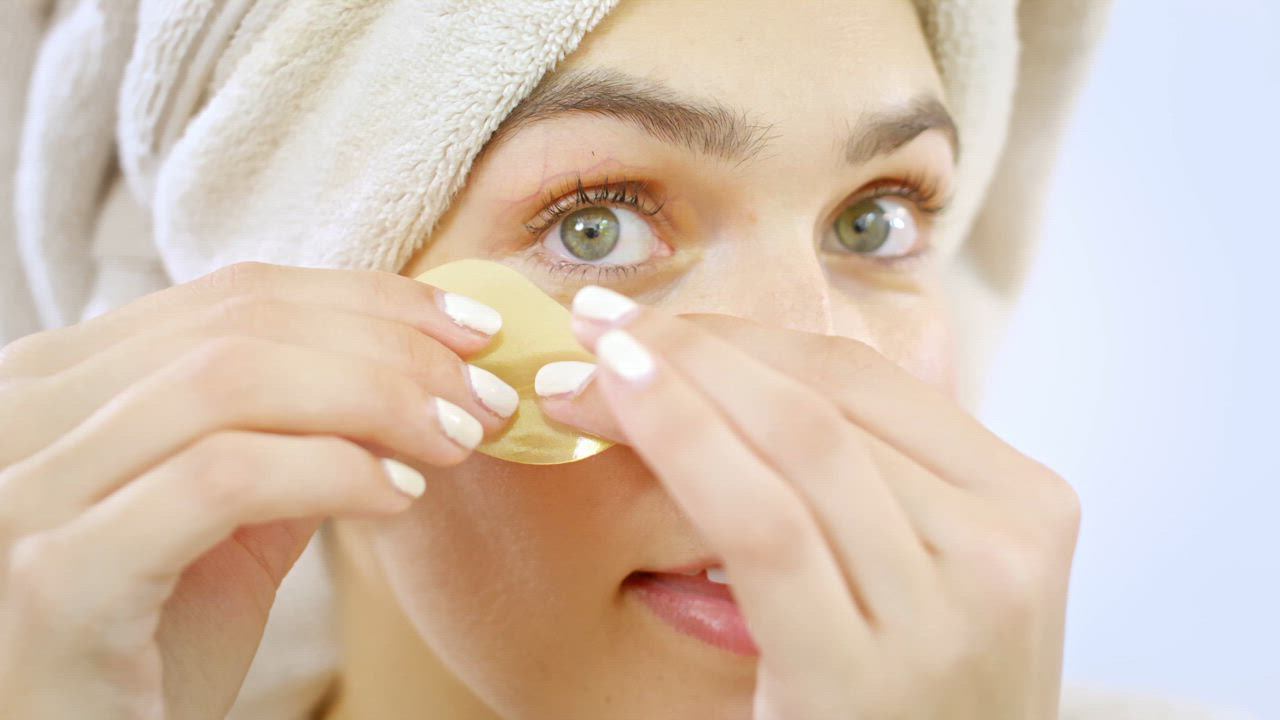 A young woman puts an eye bag patch as part of her skincare morning ...