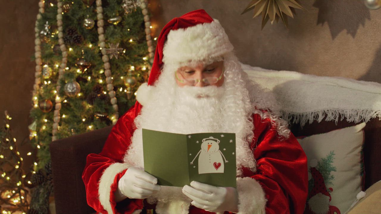 Santa Claus joyously assents while he reads a wish letter sitting on a ...