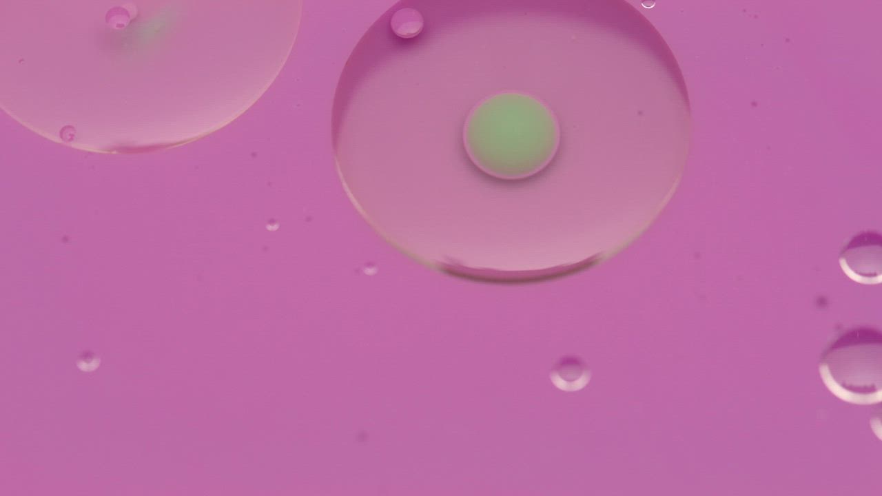 Ink drops in oil on a pink background - Free Stock Video