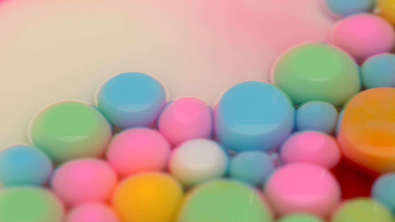 Close up of colorful ink balls on a pink layer - Free Stock Video