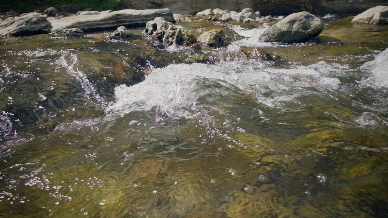 Water in slow motion flows down the river creating a foam and waves ...