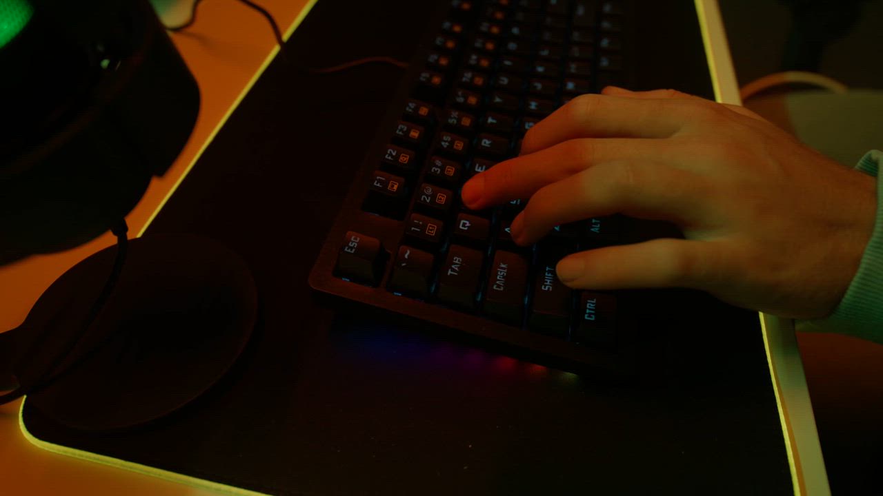 Camera hovers over a hand on a backlit keyboard - Free Stock Video