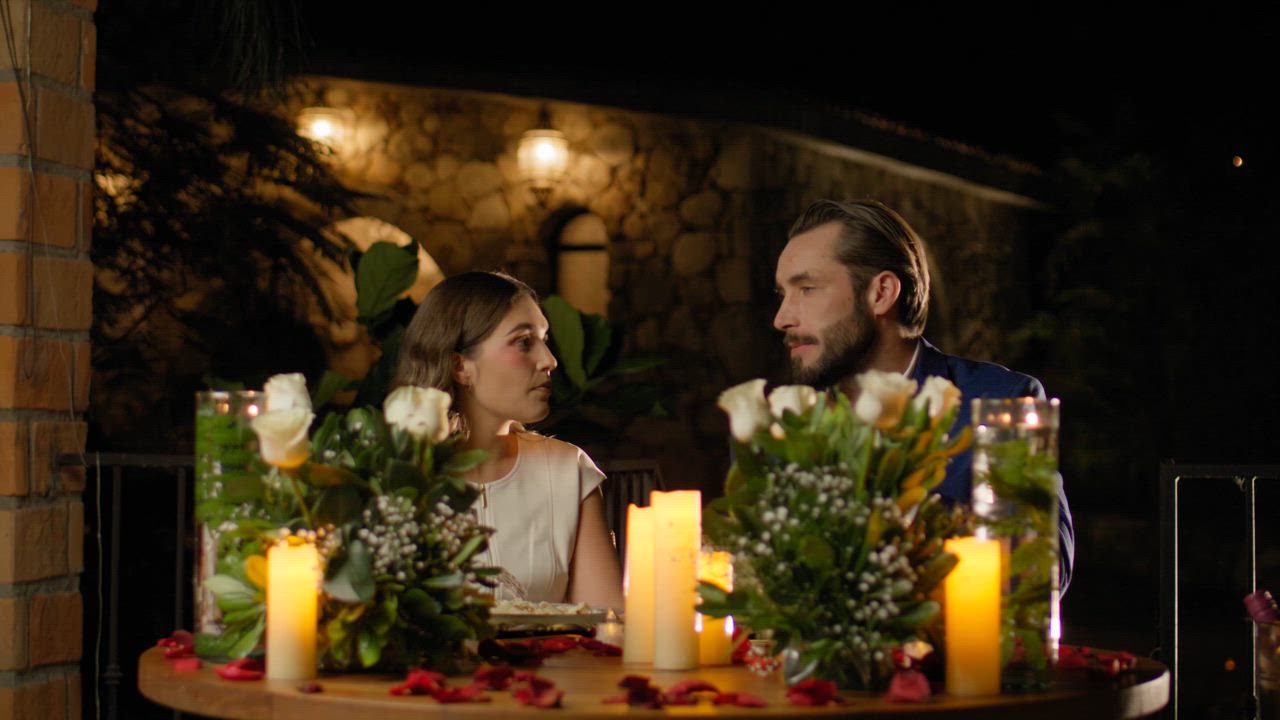 A young couple engages in conversation at a romantic adorned table with ...
